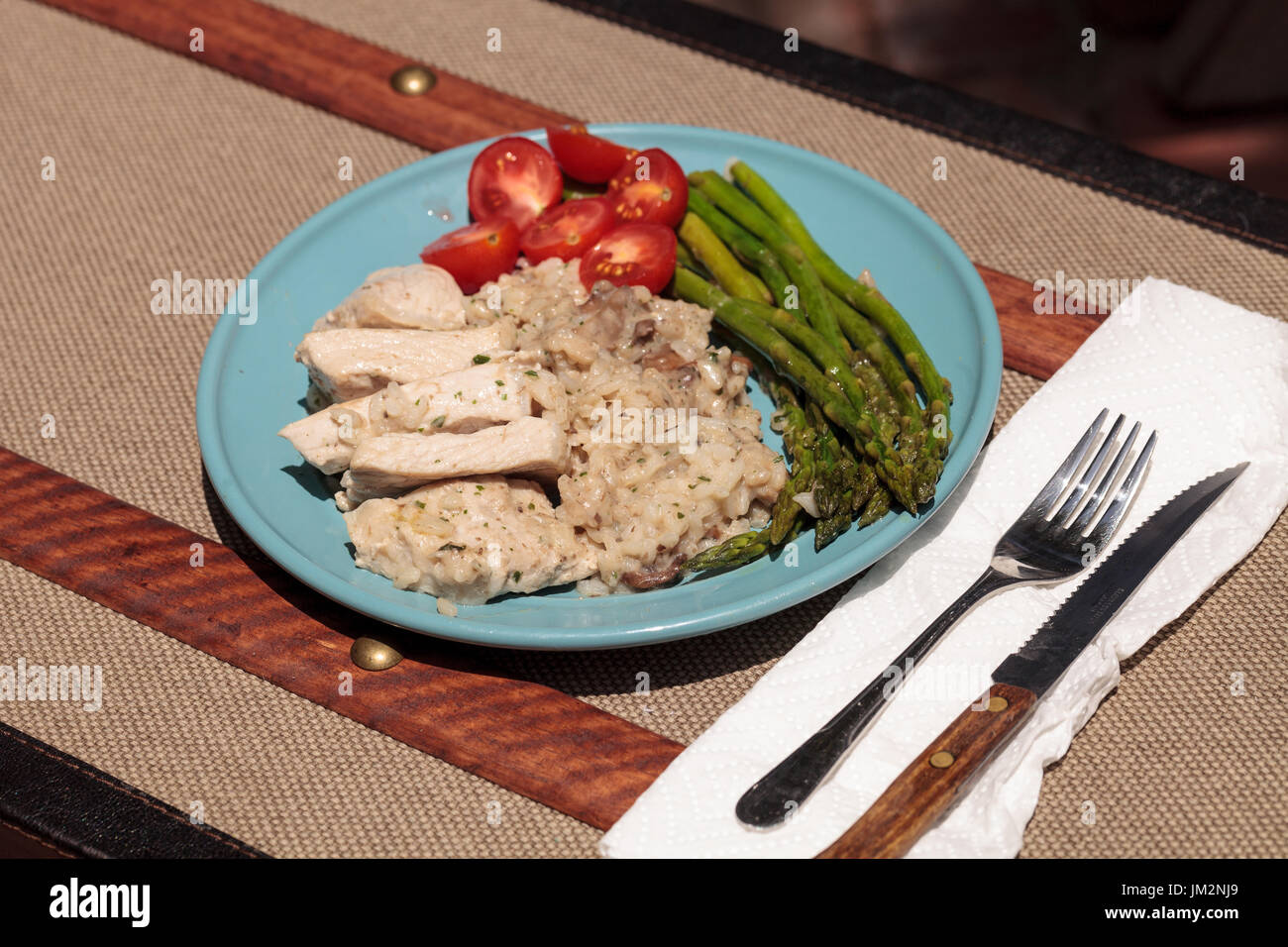 Sauteed pork and asparagus with mushroom risotto meal on a rustic ...