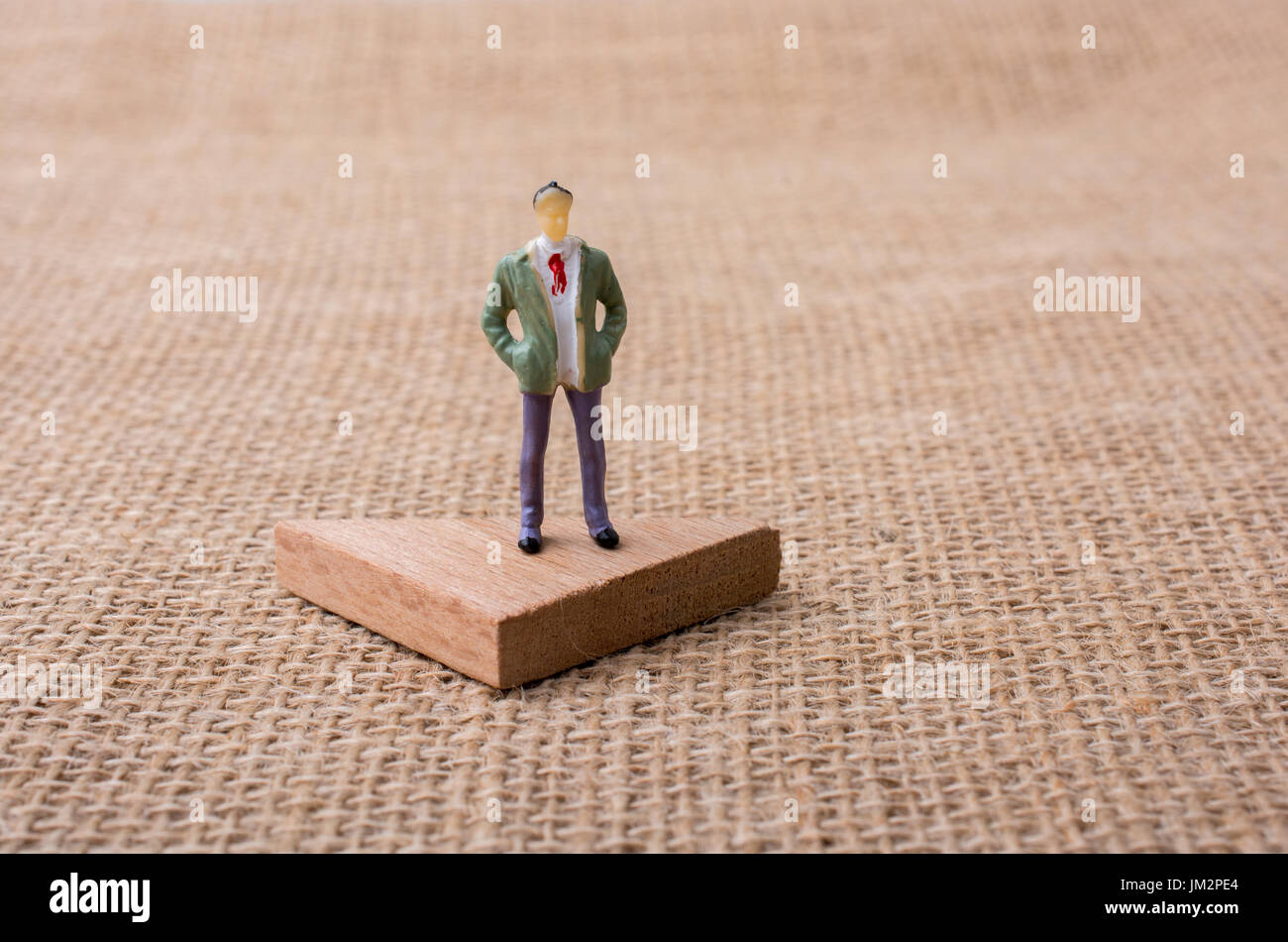 Man figurine standing on a triangle piece of wood Stock Photo - Alamy
