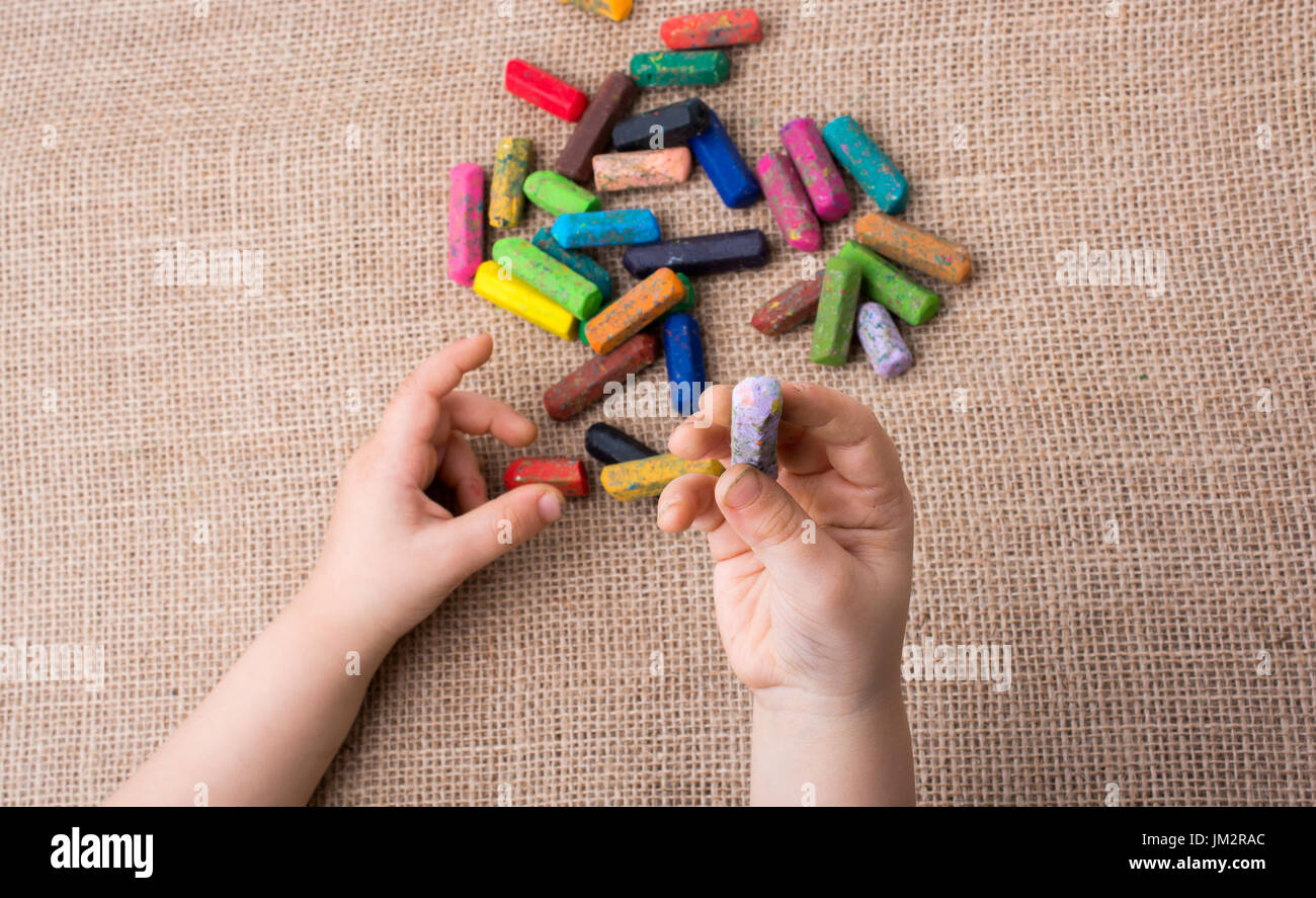 Used color crayons and a toddlers hand holding one Stock Photo - Alamy