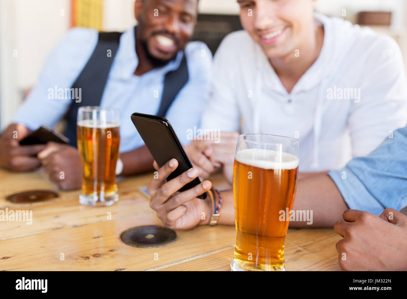 Smiling friends drinking beer together hi-res stock photography and ...
