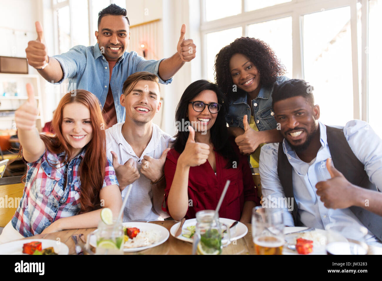 happy friends showing thumbs up at restaurant Stock Photo - Alamy