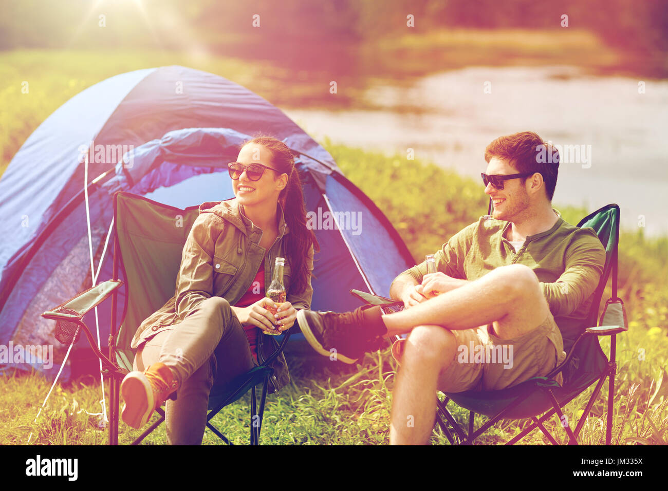 happy couple drinking beer at campsite tent Stock Photo - Alamy
