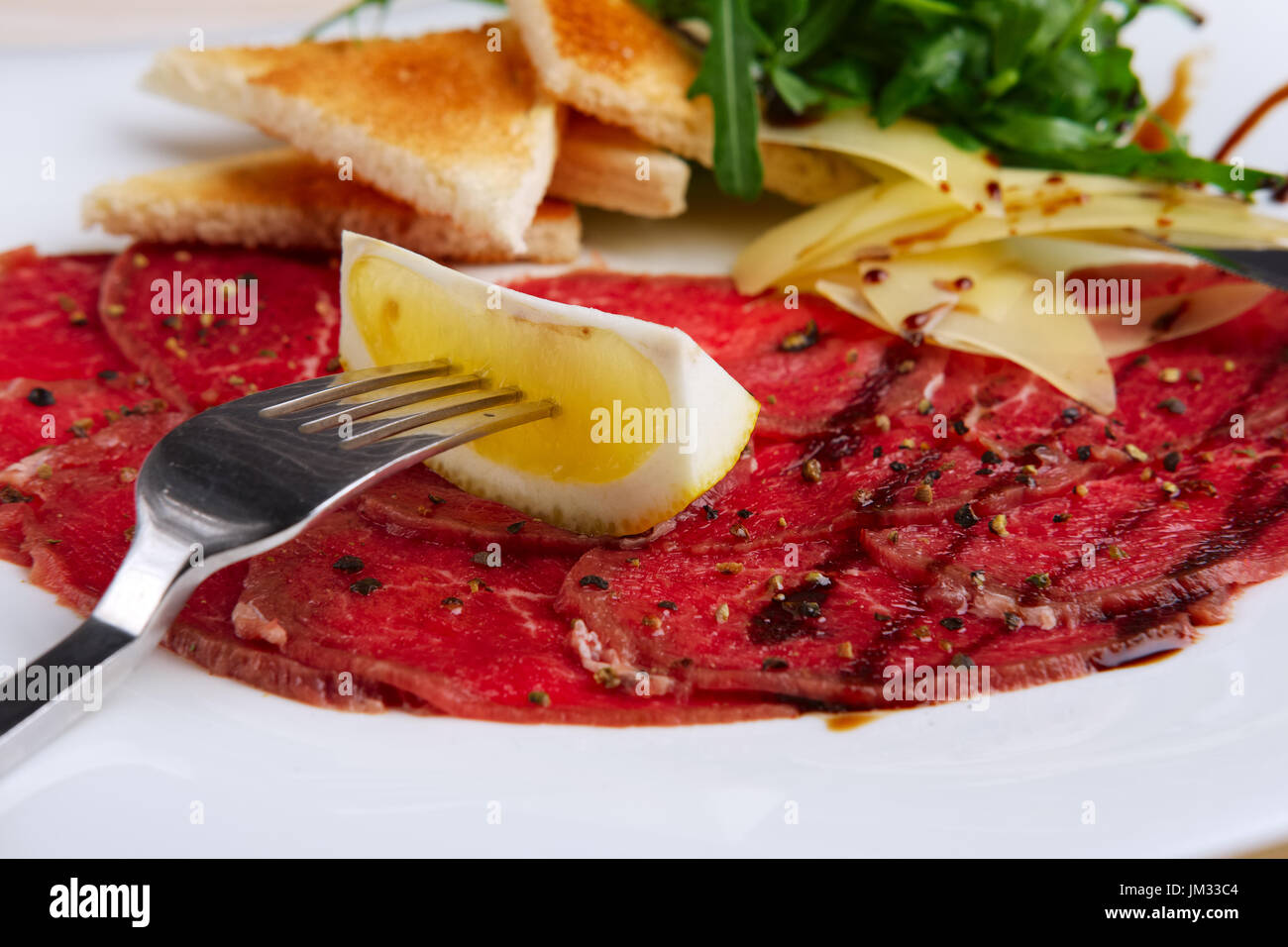 Closeup view of beef carpaccio with cheese, white bread toasts and ...
