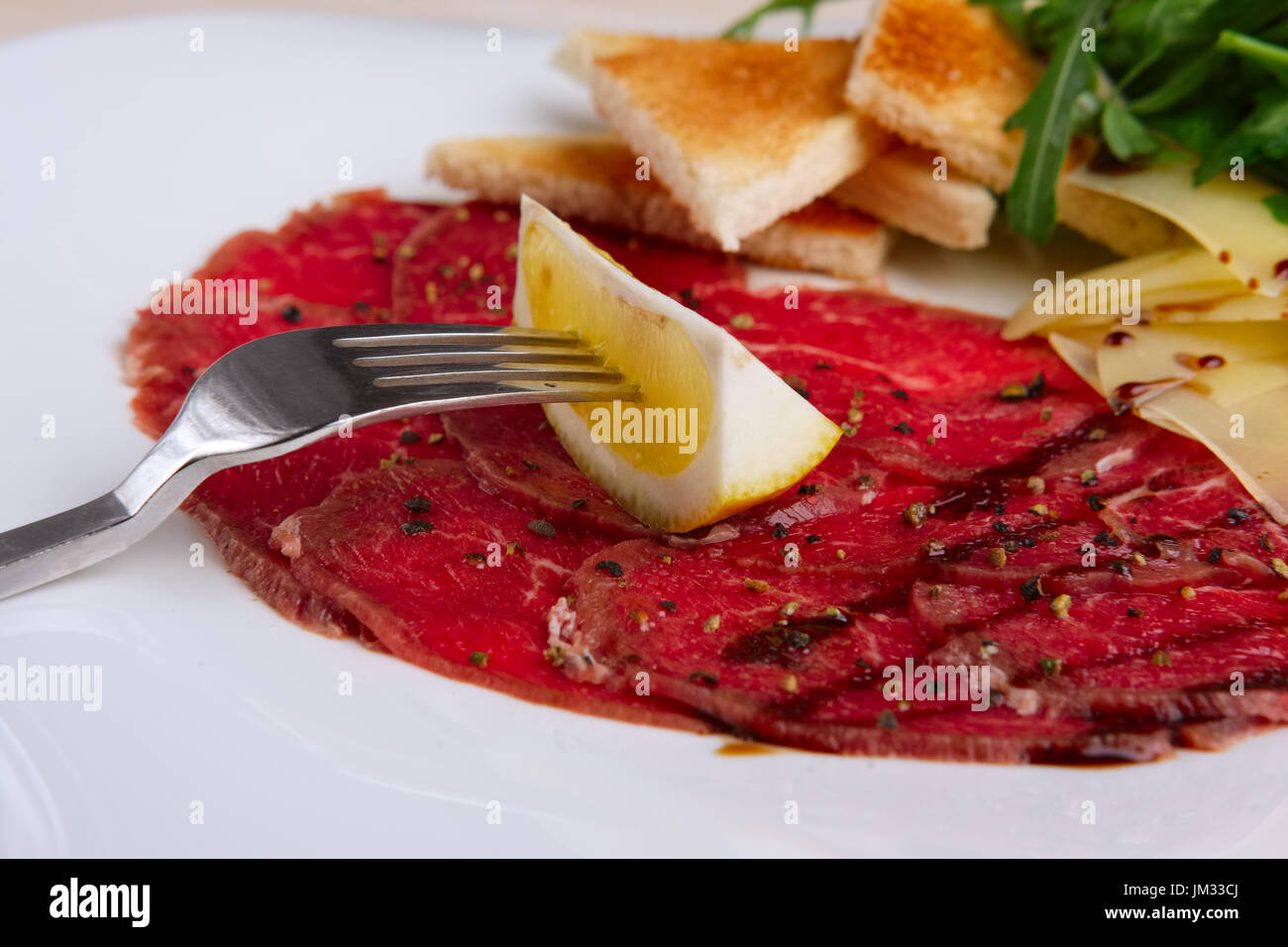 Closeup view of beef carpaccio with cheese, white bread toasts and ...