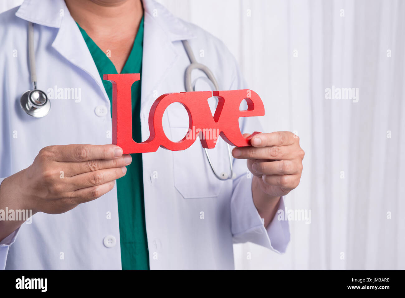 Asian male doctor with stethoscope holding LOVE letters, isolated on ...