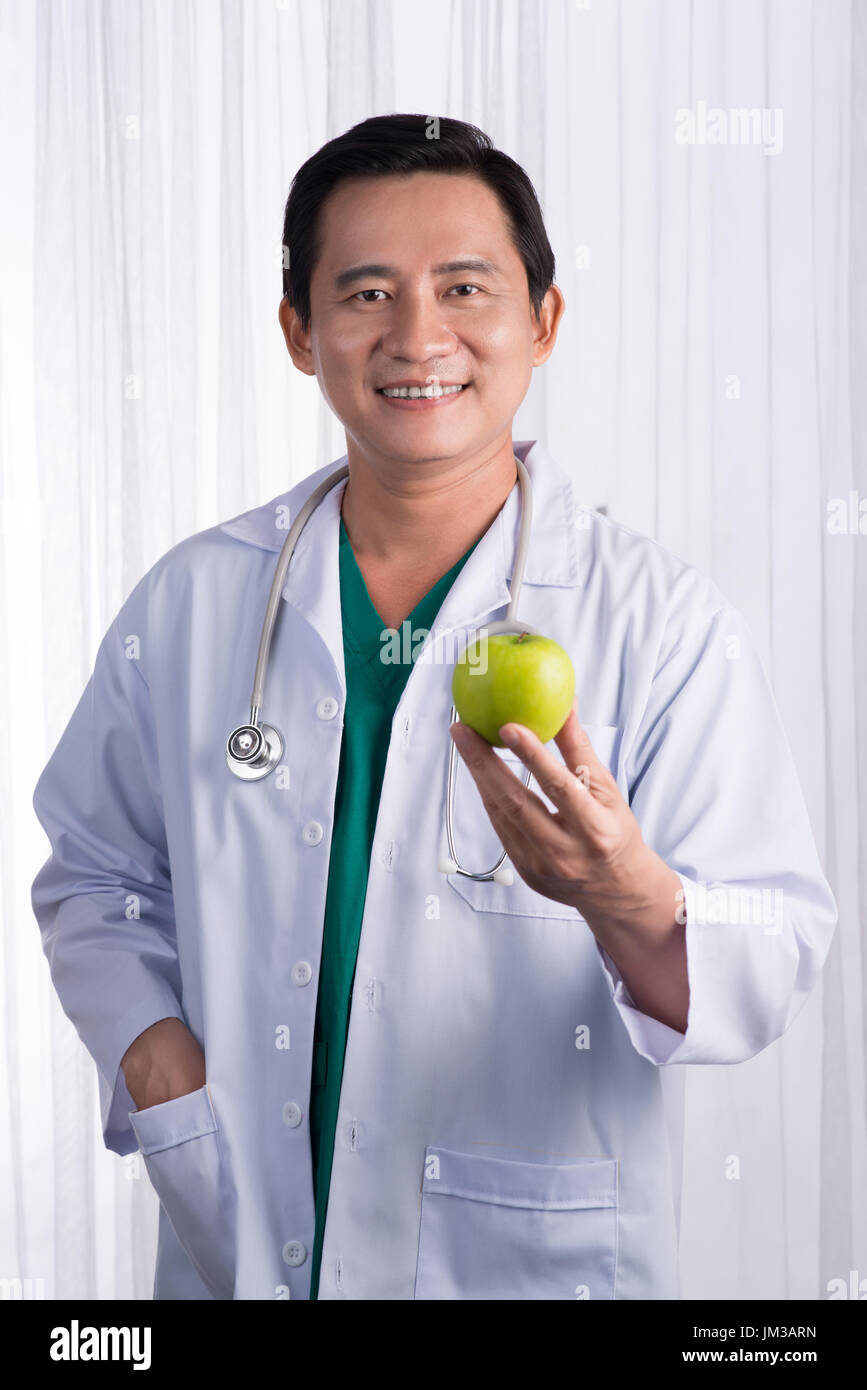Nurse or male doctor giving an apple smiling. Health care concept ...