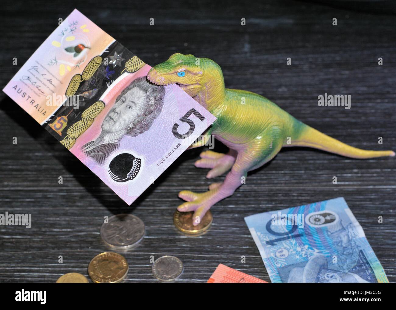 Selective focus on Australian dollar five note in dinosaur's mouth with ...