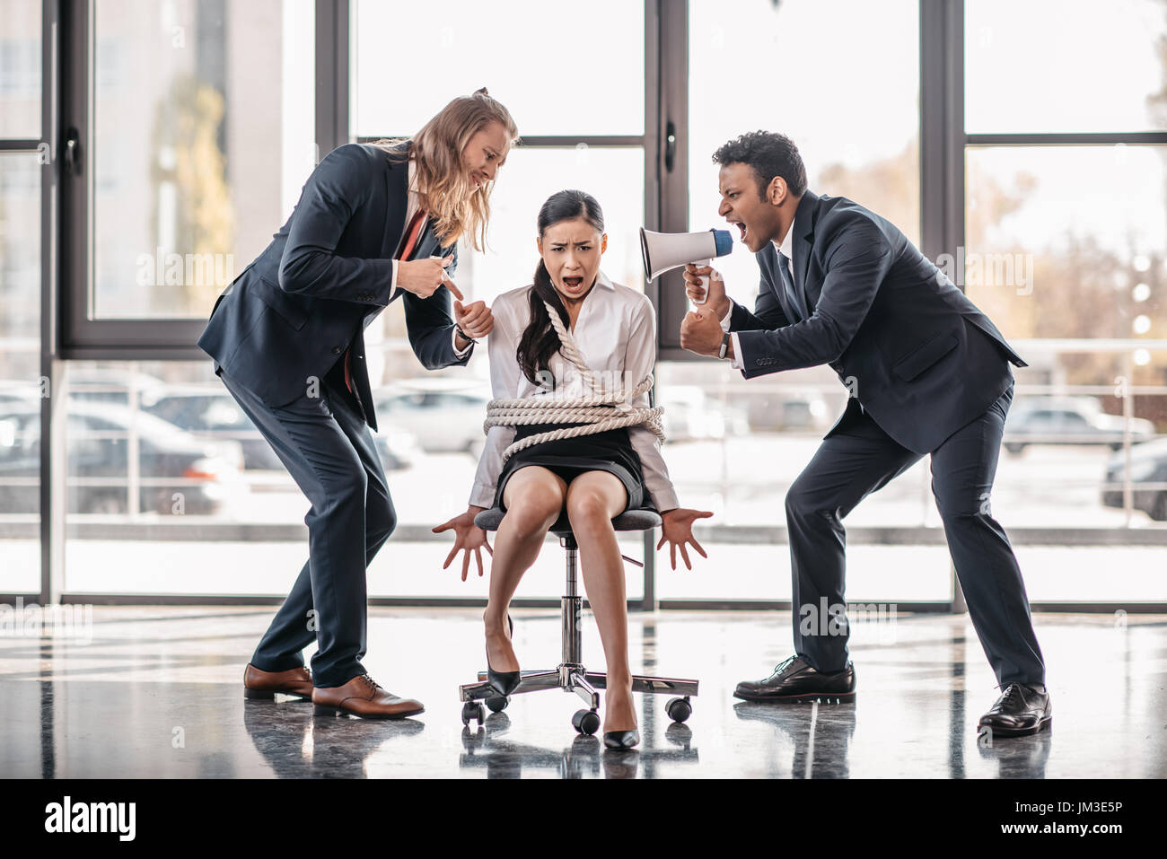 yelling asian businesswoman bound with rope on chair while businessmen ...