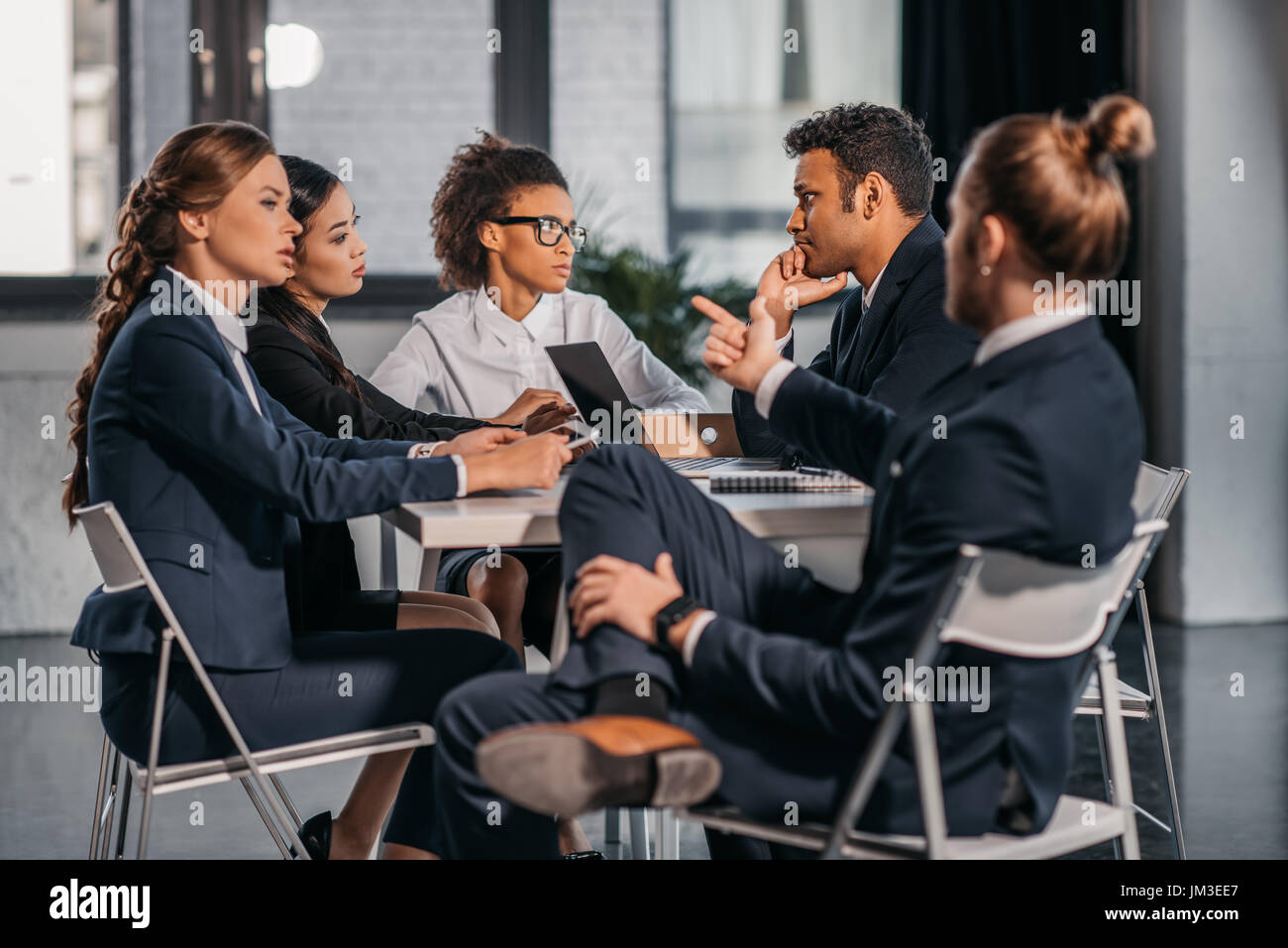 young coworkers in formalwear arguing at business meeting in office ...