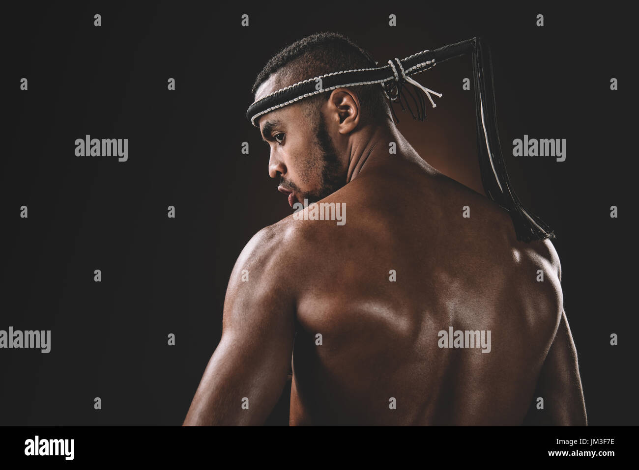 Back view of muscular shirtless Muay Thai fighter looking over shoulder ...