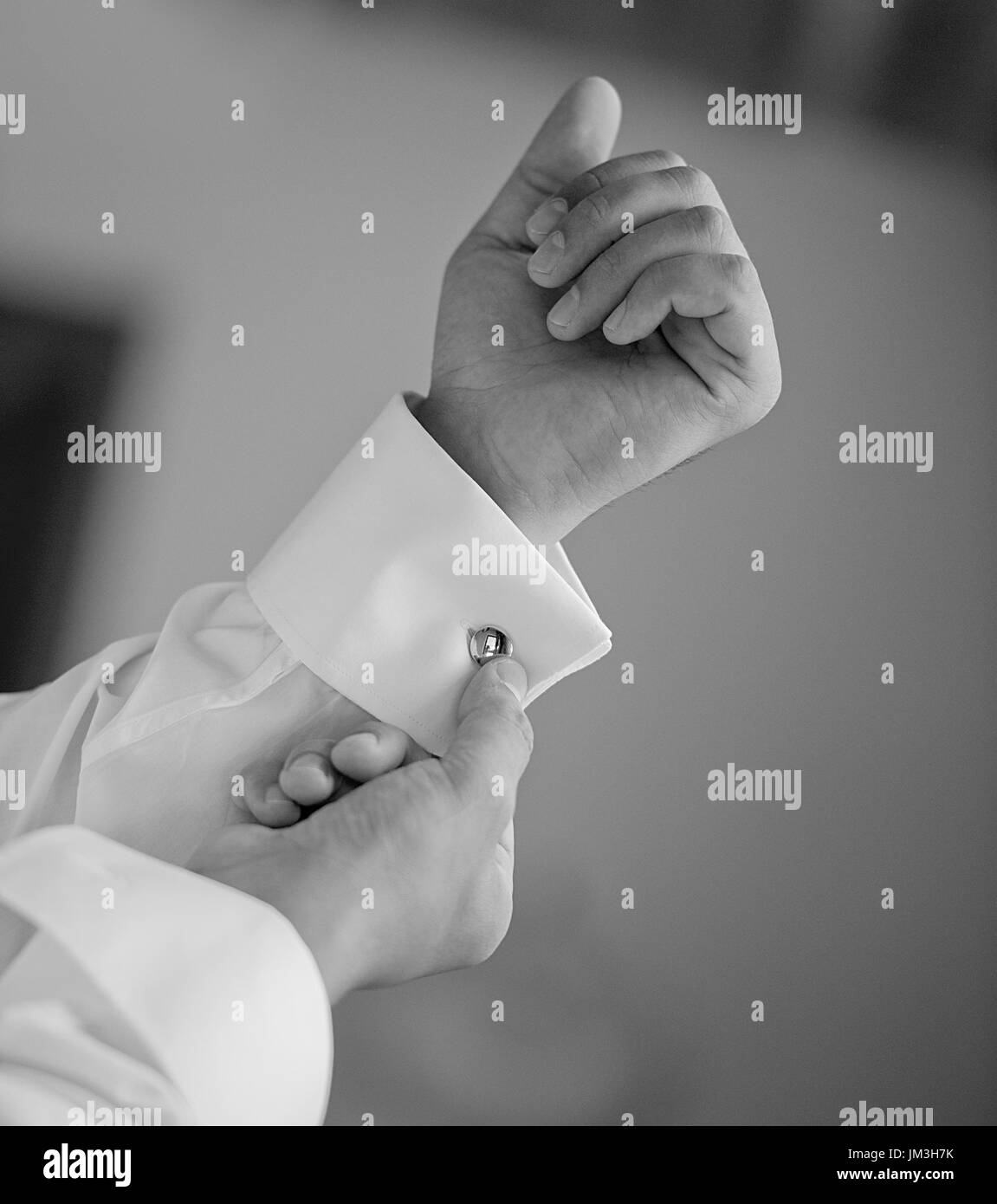 man buttoning on the sleeve of his shirt, black and white photography ...