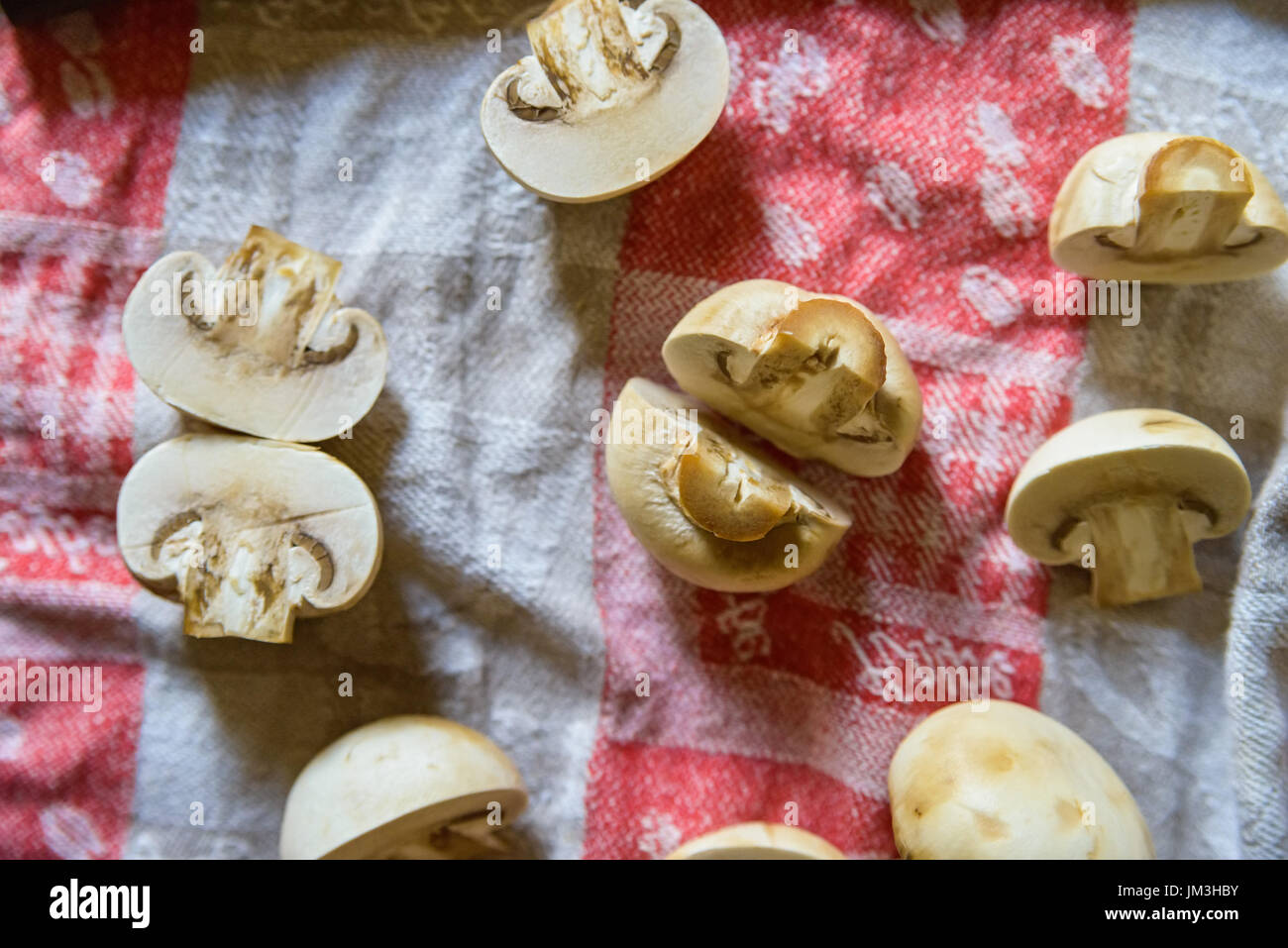 Close up fresh mushrooms cut in halves and old knife lying on cloth for ...