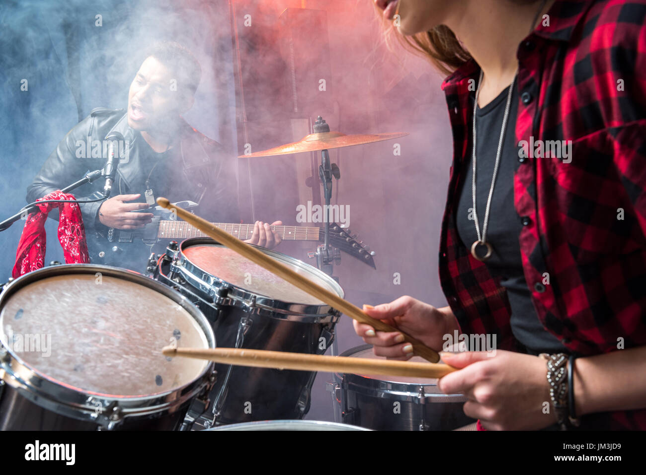side view of woman playing drums and man singing into microphone, rock ...