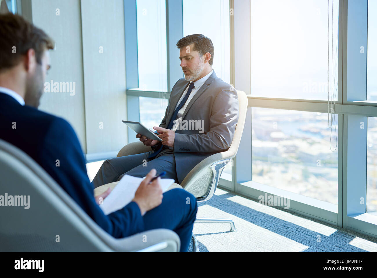 Mature business executive reading information on a digital tablet, with ...