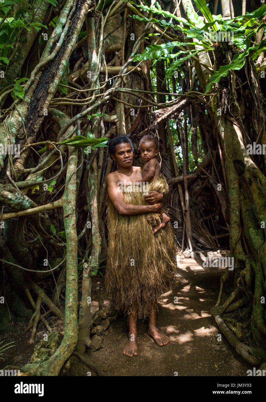 Woman with her baby in traditional skirt standing under a banyan tree ...