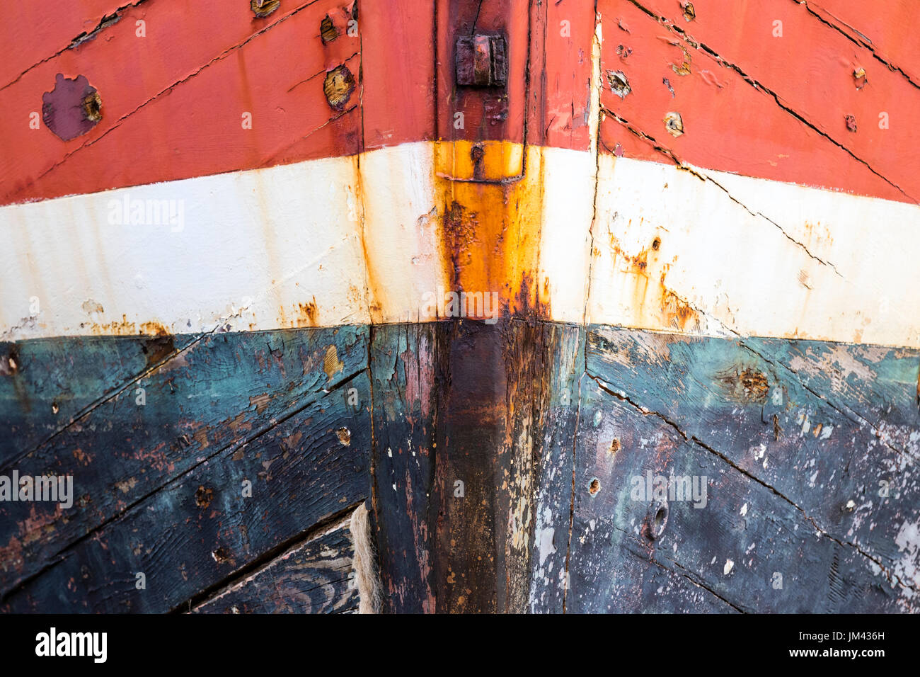 Close up of bow of old derelict ship docked on dry land. Red and blue ...
