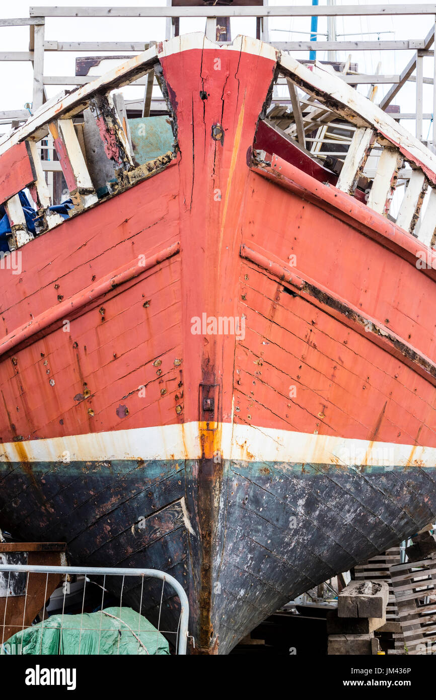 Matt red painted bows of old dry-docked boat. Woodwork crumbling with ...