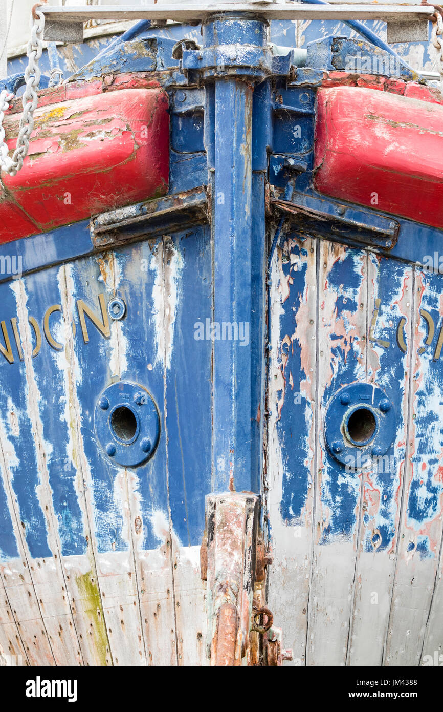 Dry docked former lifeboat. Bows with blue paint peeling and heavily ...