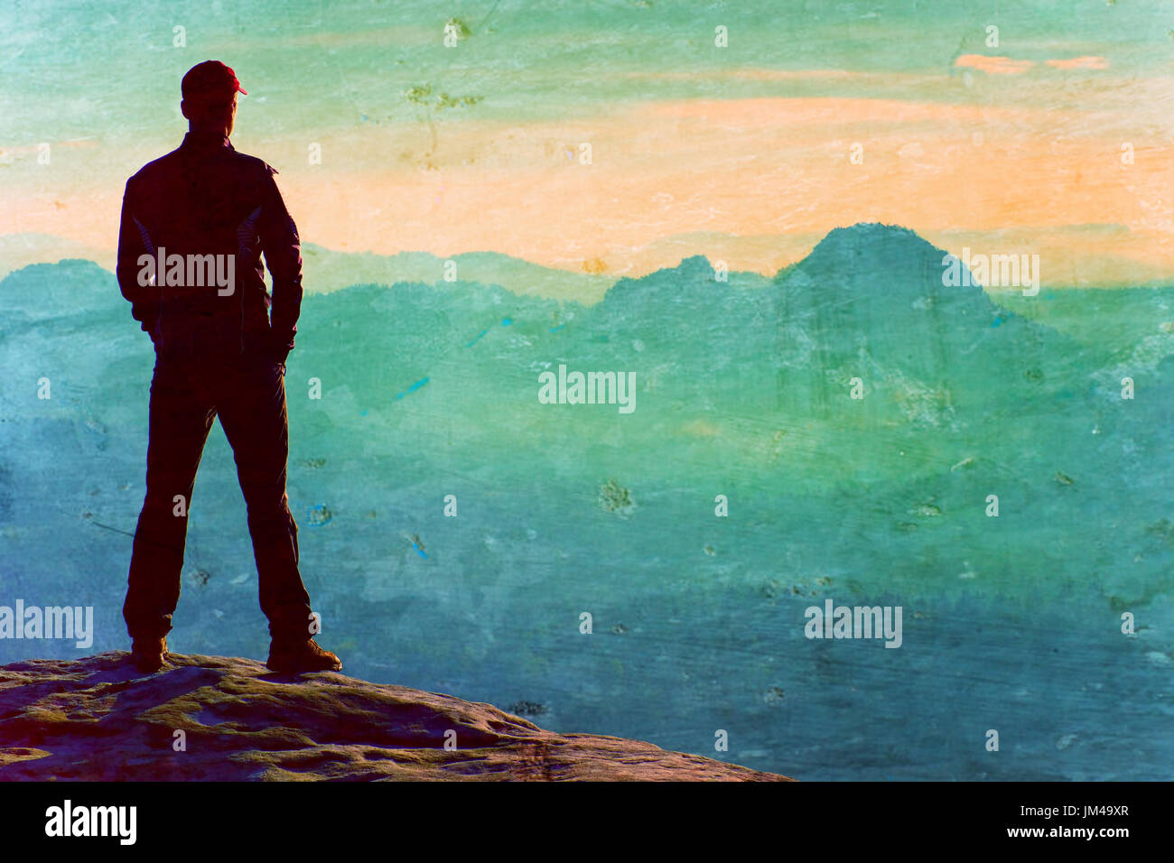 Film grain effect. Hiker is standing on the peak of sandstone rock in ...