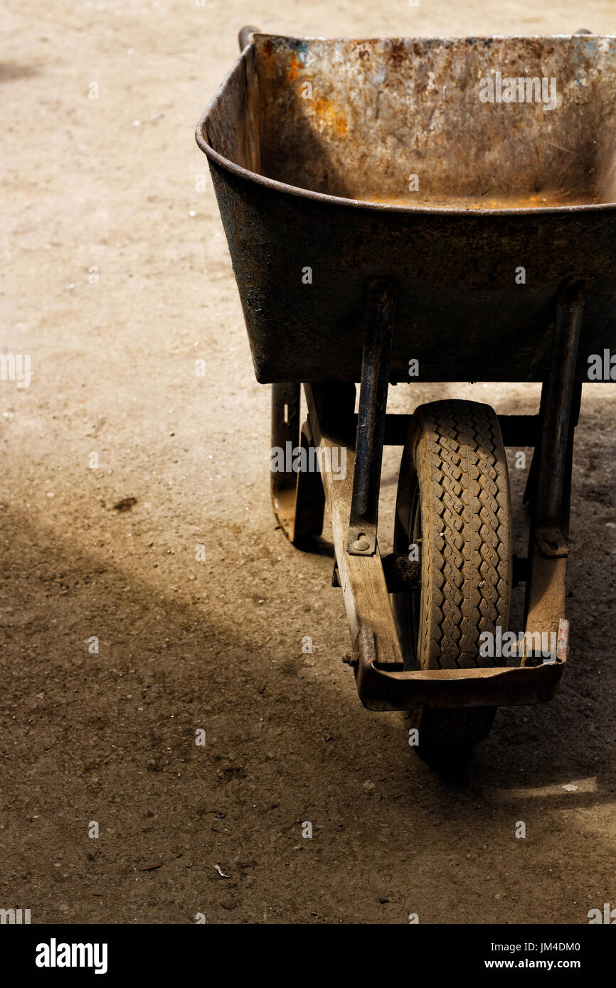 an old, rusty wheelbarrow in a dusty yard of dirt Stock Photo - Alamy