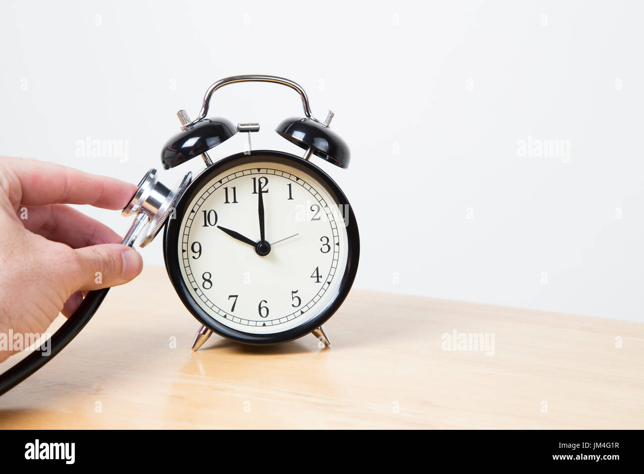 Man checking clock with a stethoscope - time concept Stock Photo - Alamy