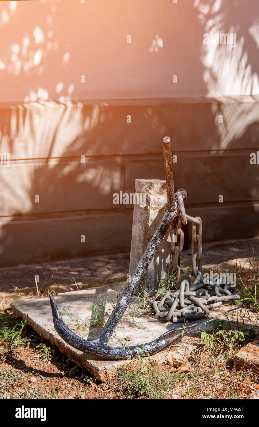 Old rusty anchor on land at the stone wall. The vertical frame Stock ...