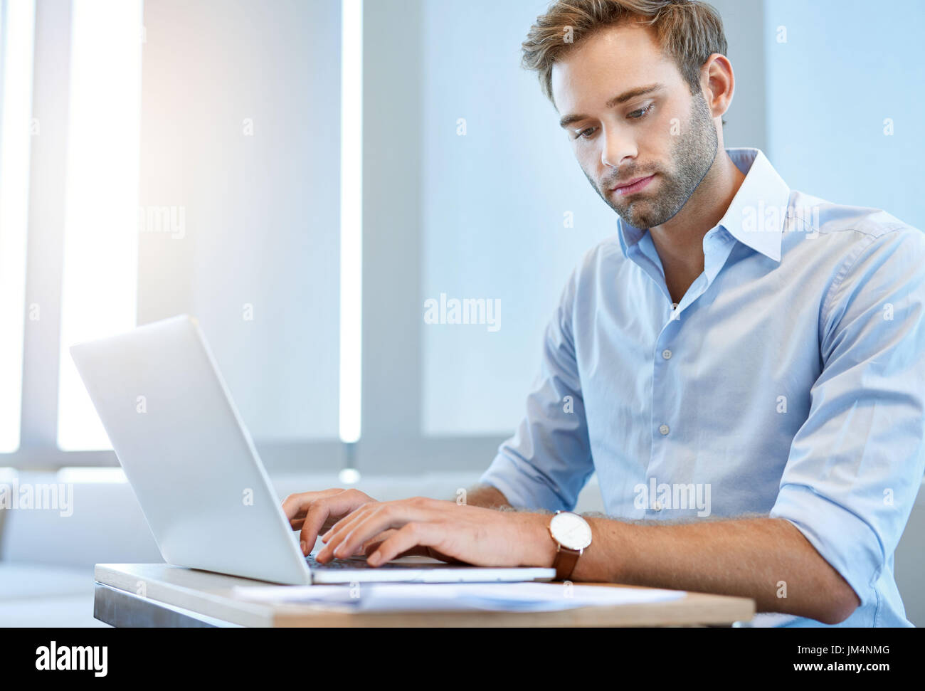 Handsome young business executive using his laptop computer to work ...