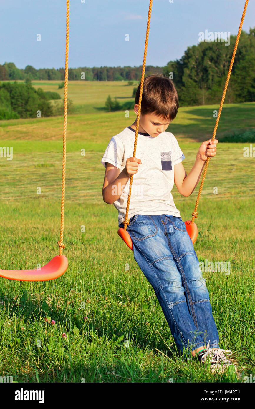 Sad lonely boy sitting on swing Stock Photo - Alamy