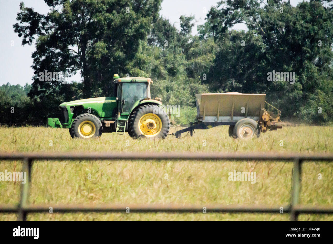 A john deere tractor towing a grain trailer in a field Stock Photo - Alamy