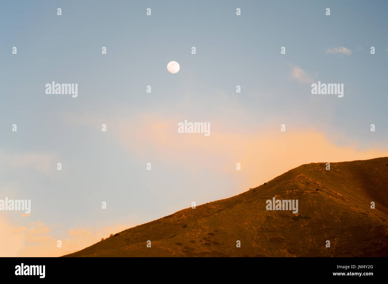 A full moon hanging over a mountain at sunset Stock Photo - Alamy