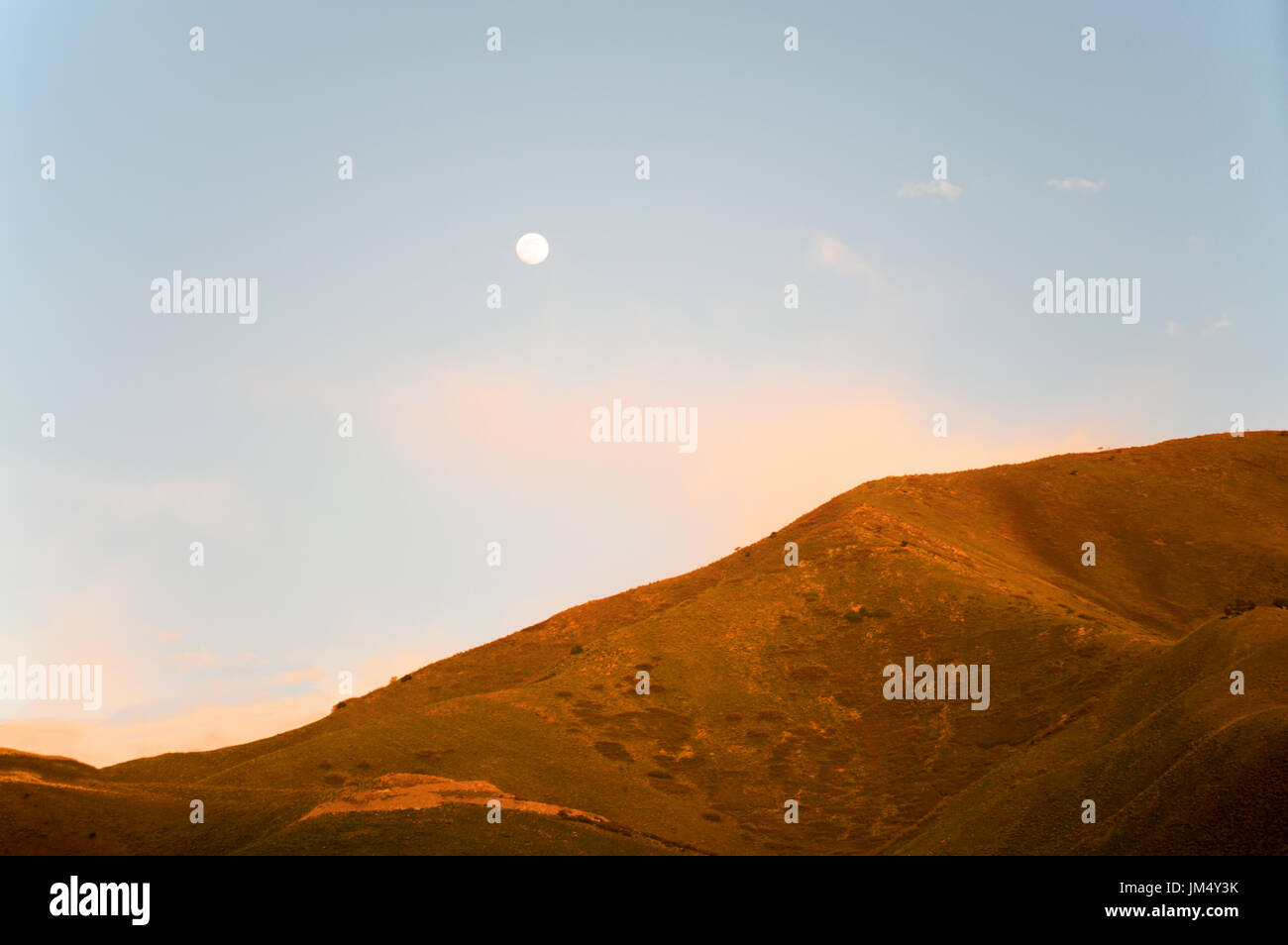 A full moon hanging over a mountain at sunset Stock Photo - Alamy