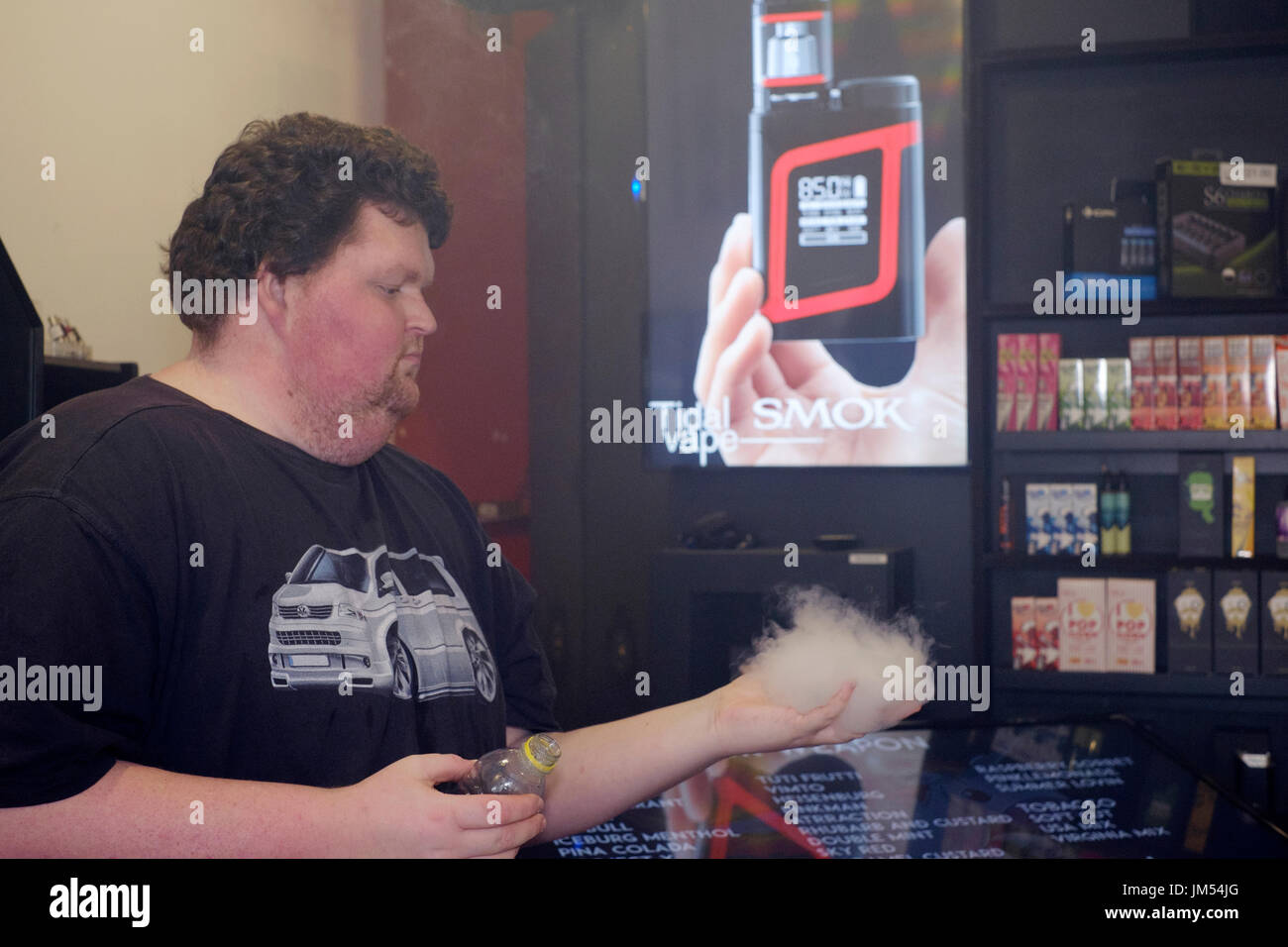 male performing tricks with electronic cigarette vapour in a vape shop ...