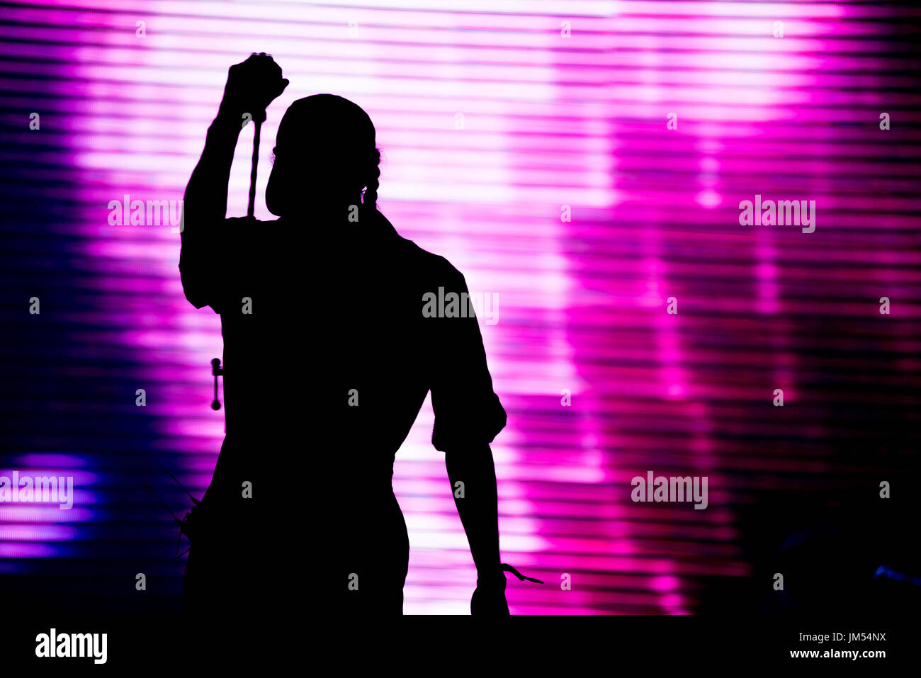 Silhouette of an artist singing live on the stage in the front of a ...