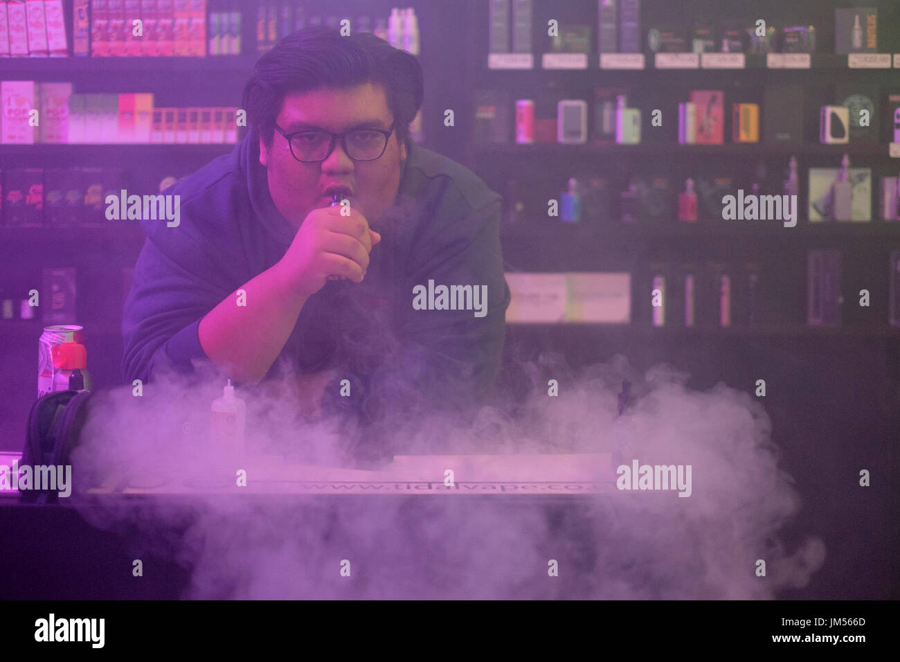 male performing tricks with electronic cigarette vapour in a vape shop ...