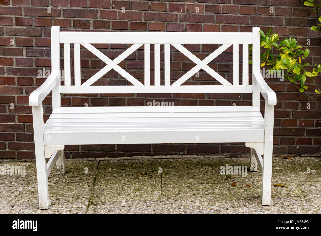 A white bench in front of a brick wall Stock Photo - Alamy