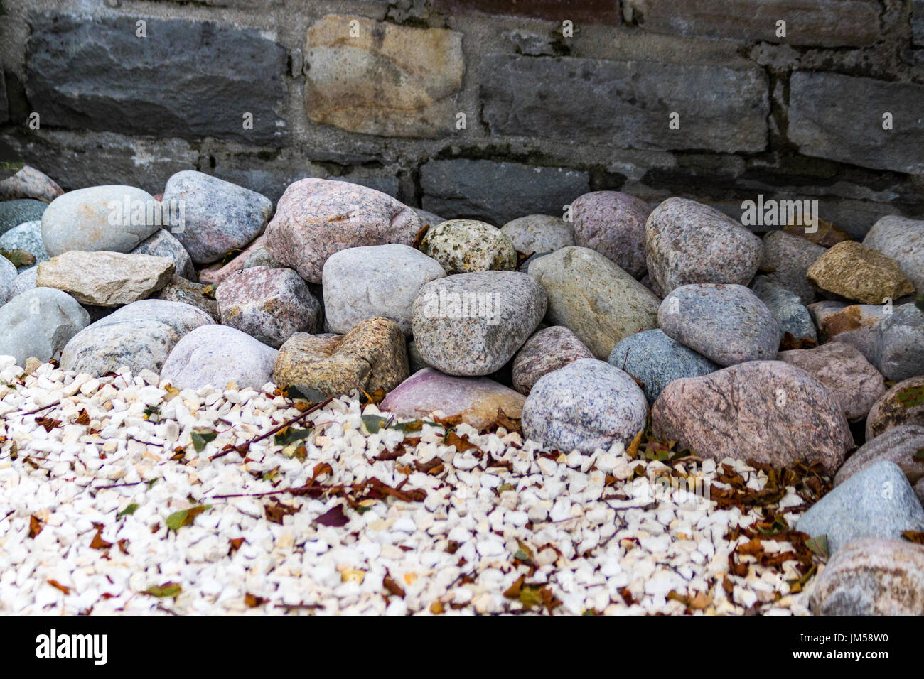 Many multicolored round stones in front of a brick wall Stock Photo - Alamy