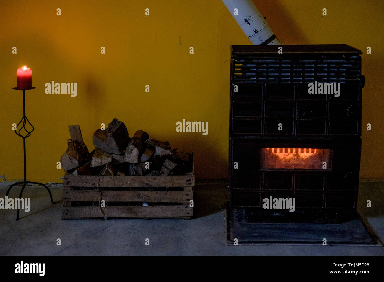 glowing wood burner and lighted candle in darkened room Stock Photo - Alamy