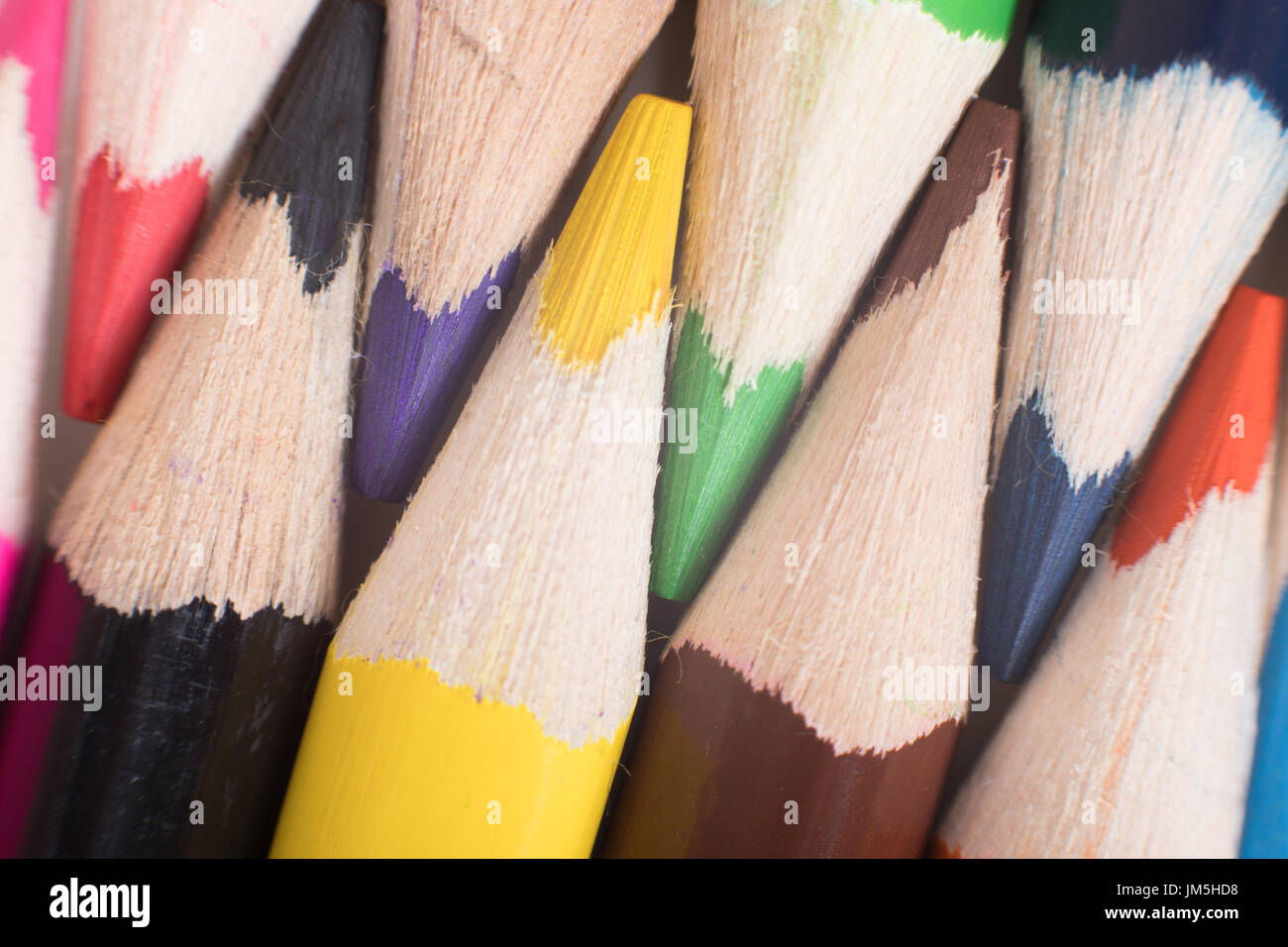 Sharpened colored pencils interleaved in background concept composition, full frame macro image ...