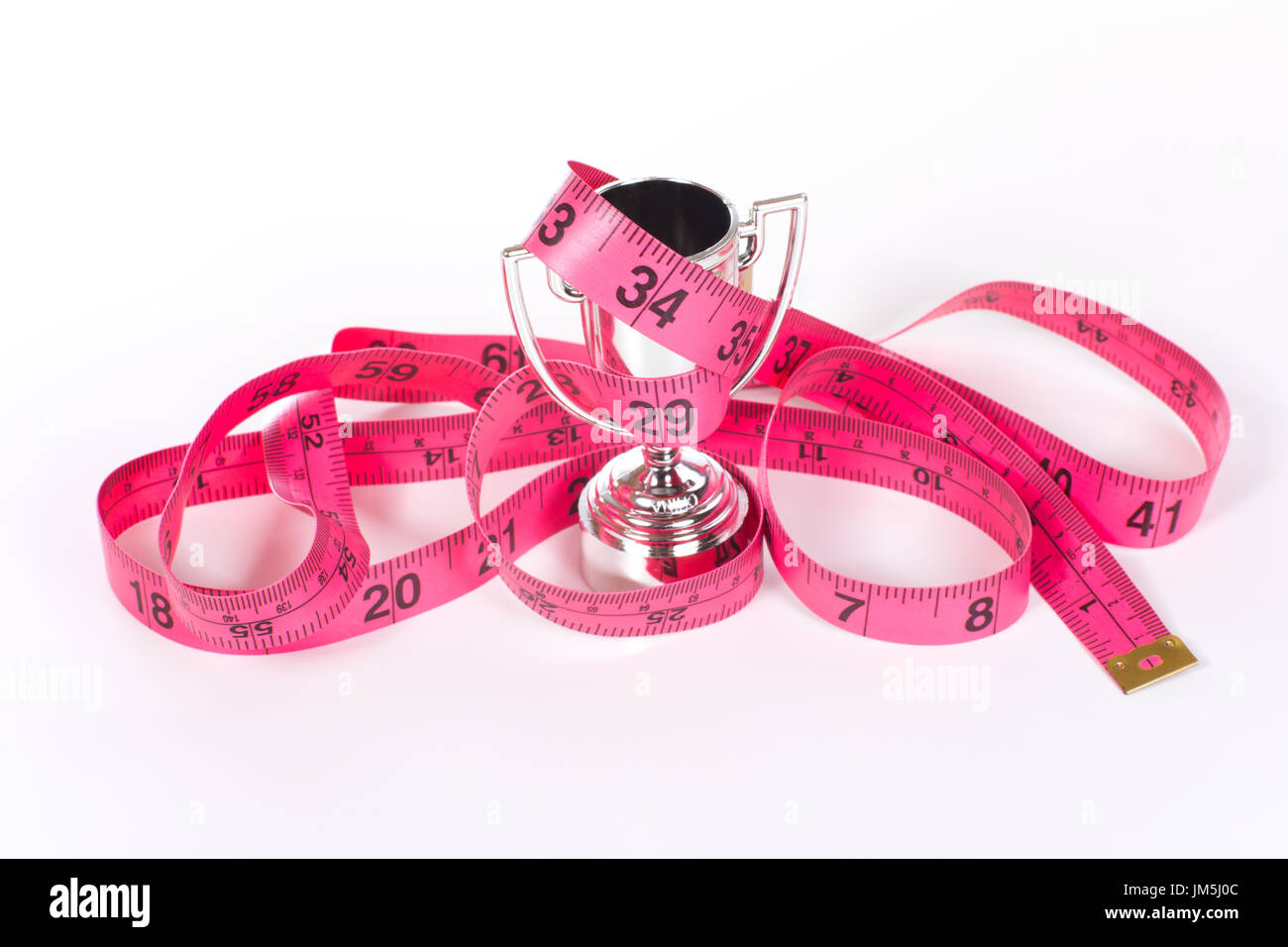 Tangled red measuring tape around small silver sports cup, viewed from ...