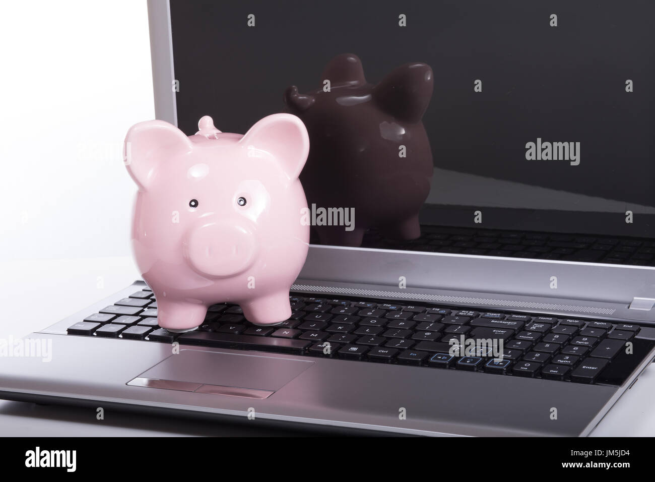Small pink piggy bank on open laptop, over black computer keyboard ...