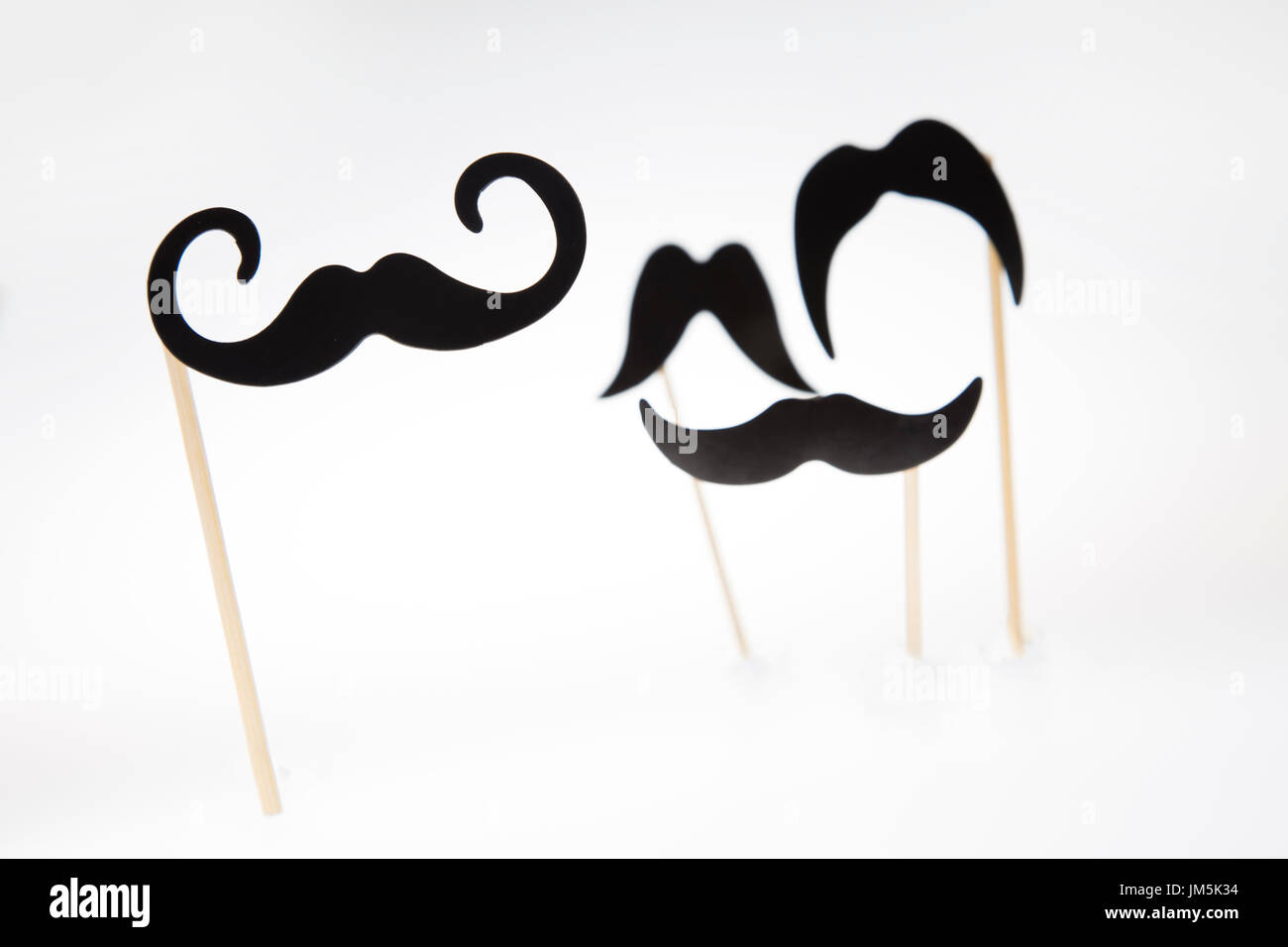 cardboard moustaches on sticks on a white background Stock Photo - Alamy