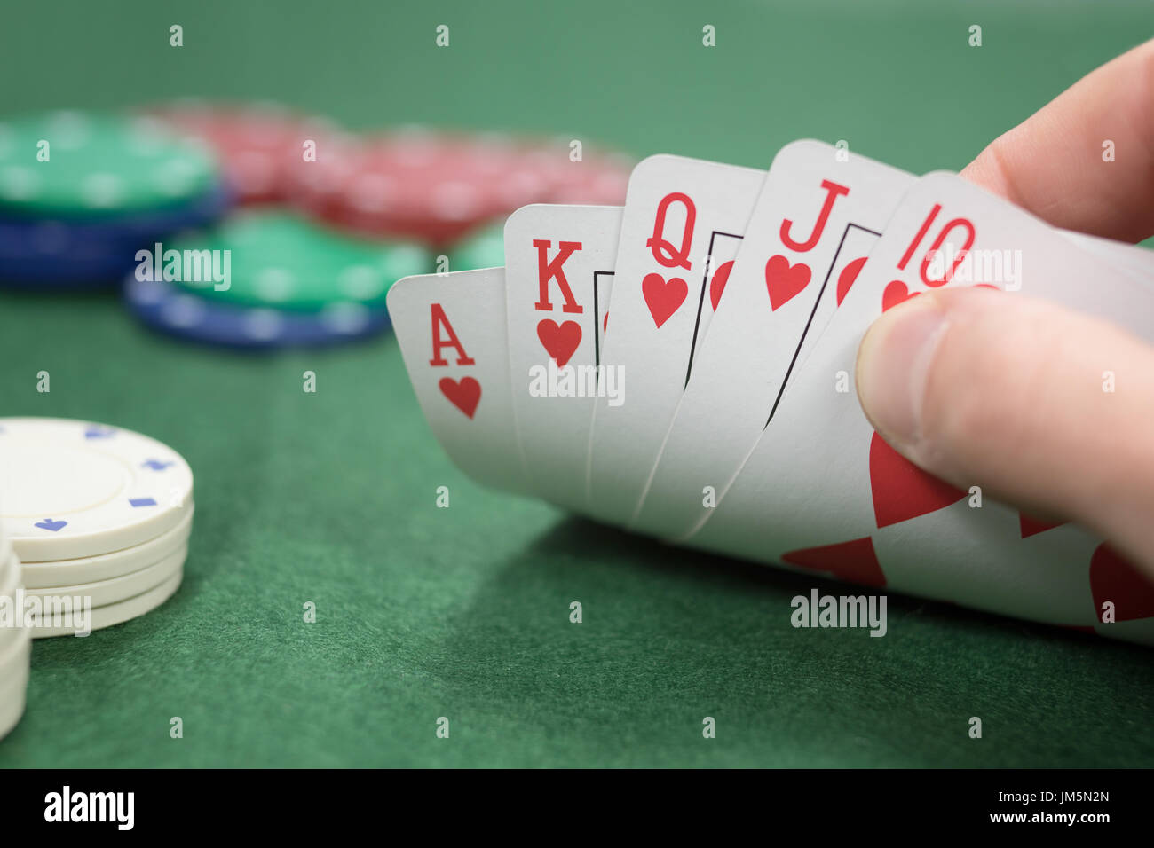 Poker player with a winning hand lifting the corner of the cards off ...