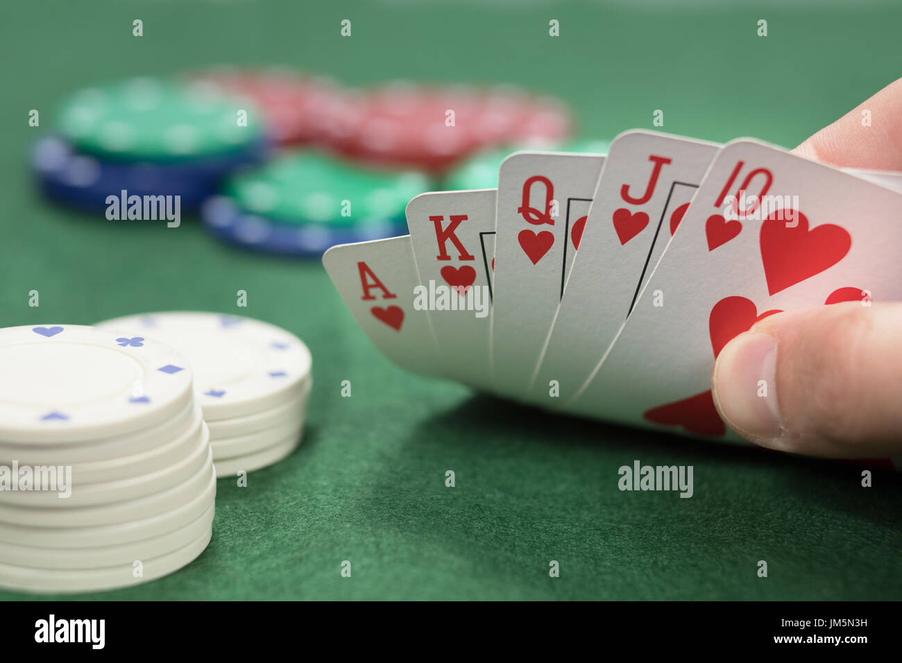 Poker player checking his royal straight flush lifting the corner of ...