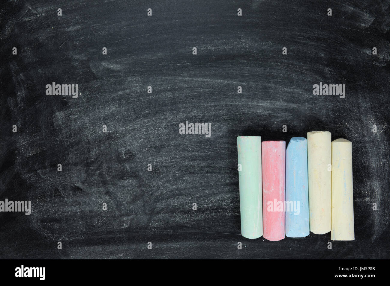 Sticks of colored chalk arranged in a neat row in the corner on a ...