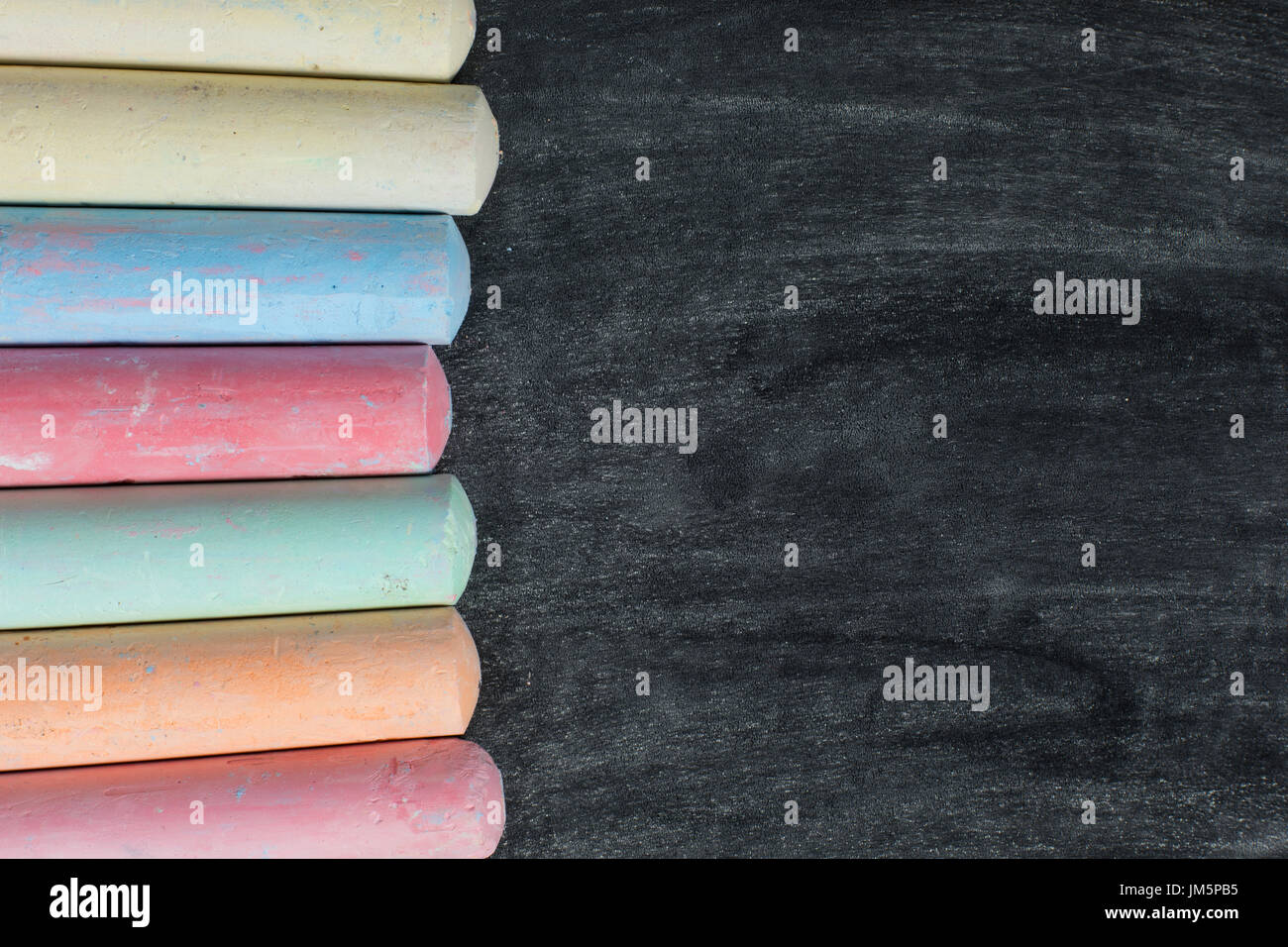 Chalk border with a neat row of multicolored sticks on a slate or ...