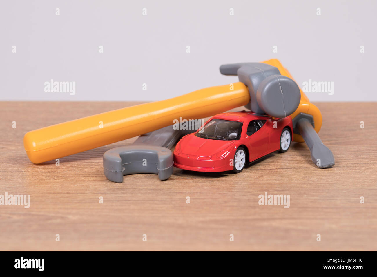 Three plastic toy tools on small model car, garage repair concept Stock ...