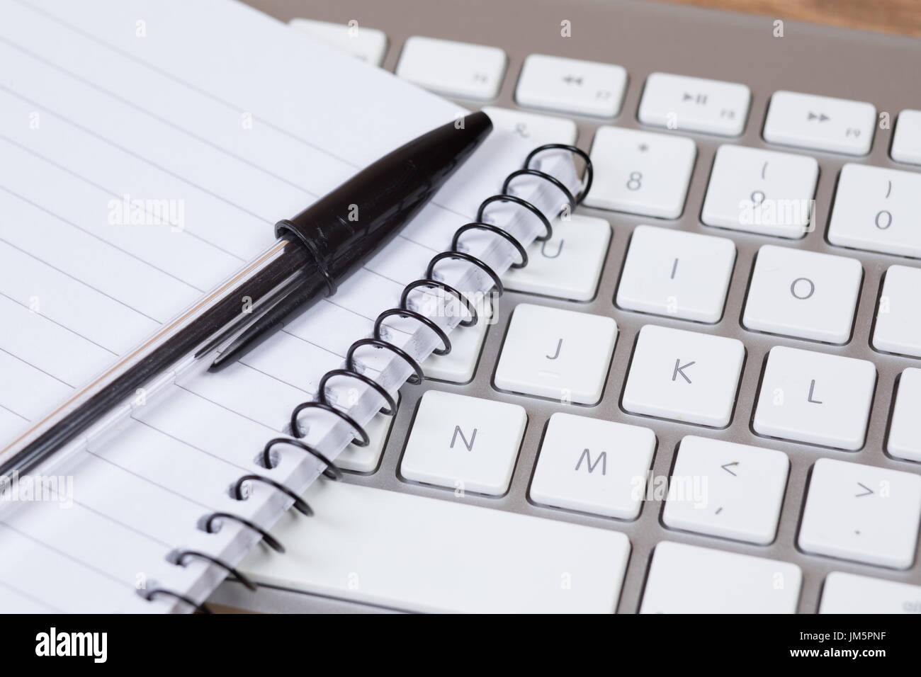 Spiral notebook and pen resting on top of computer keyboard Stock Photo ...