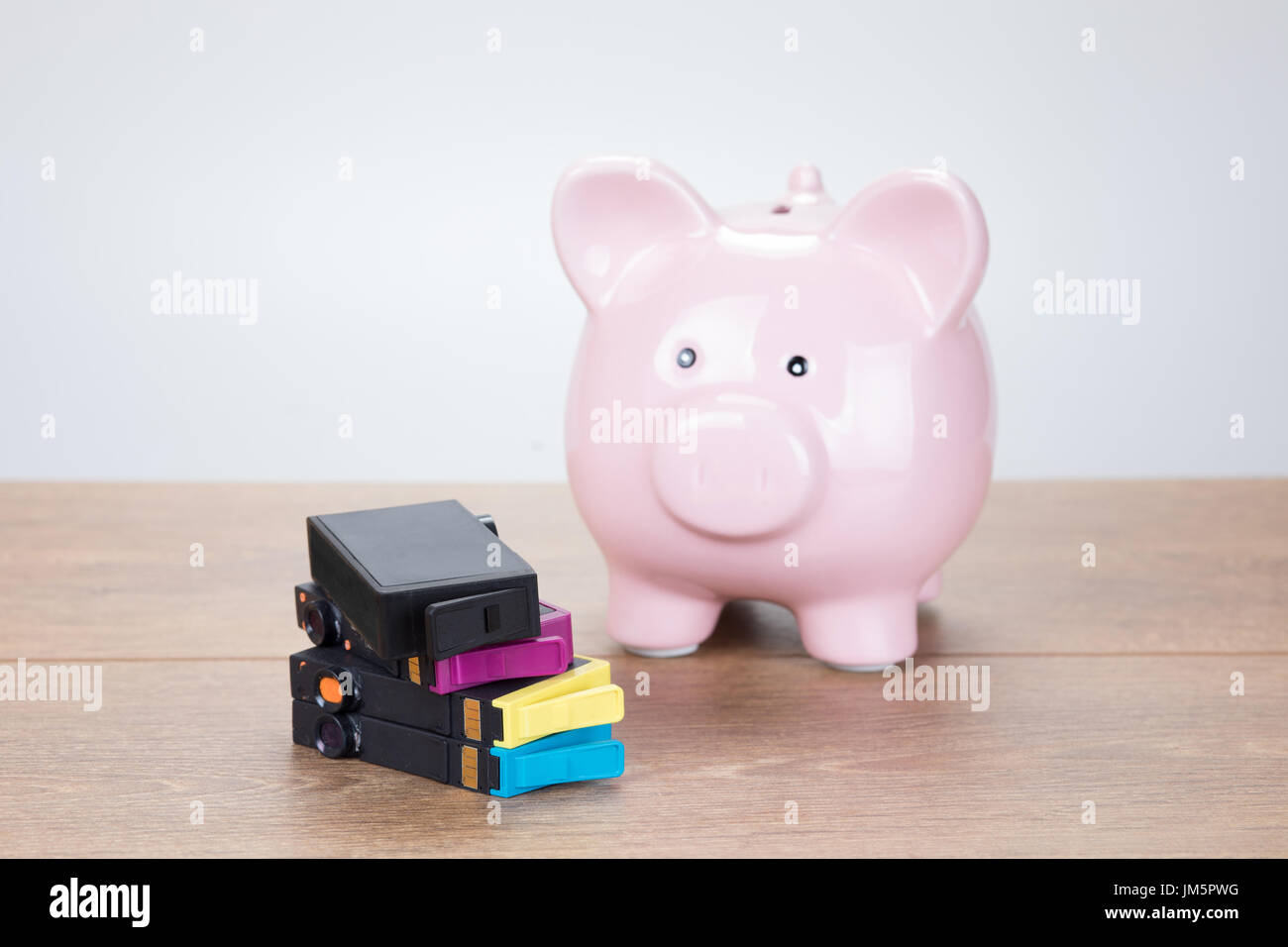 Ping piggy bank with empty CMYK printer ink cartridges alongside on a ...
