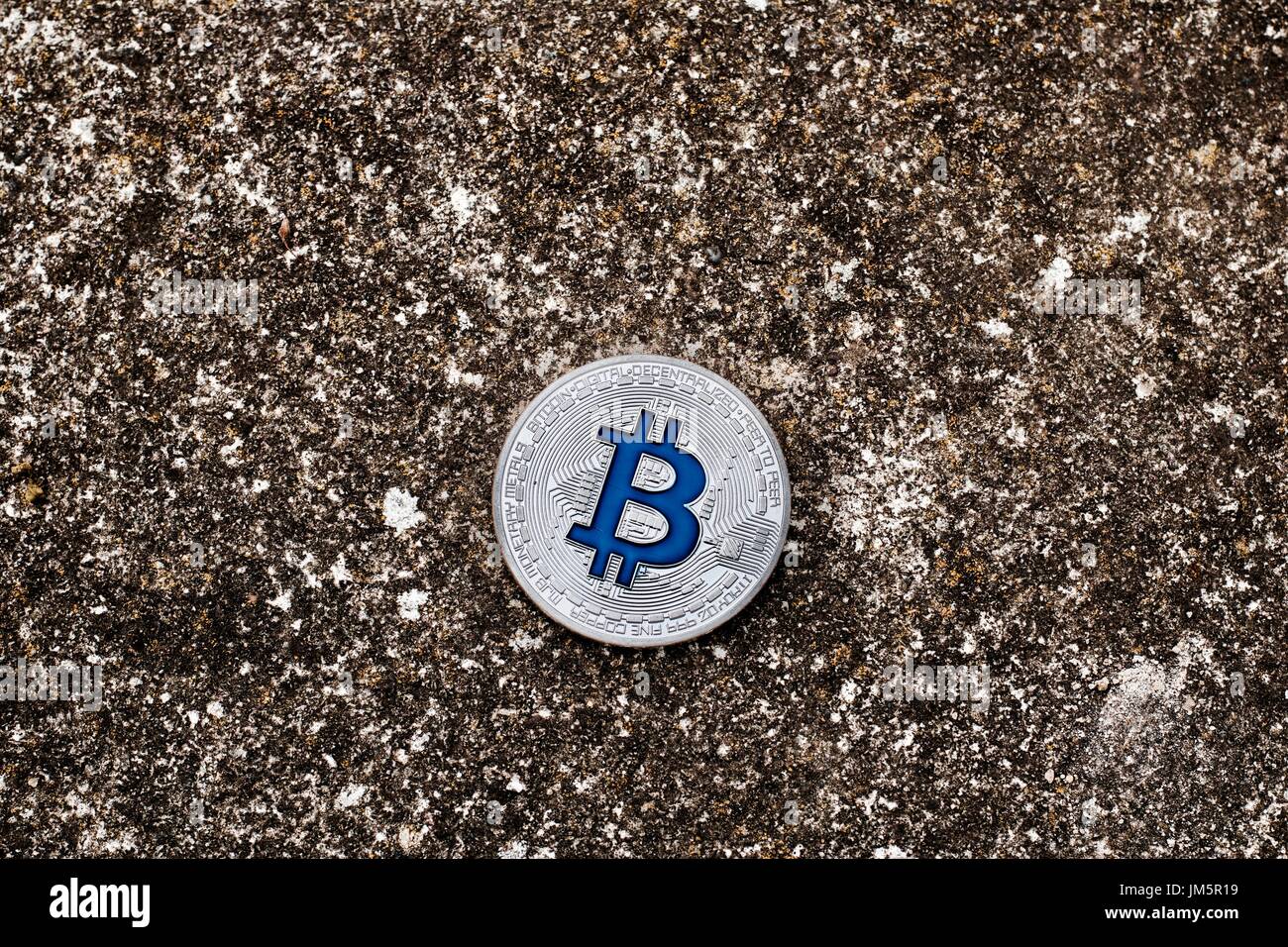Digital currency physical silver bitcoin coin with blue sign on dark ...