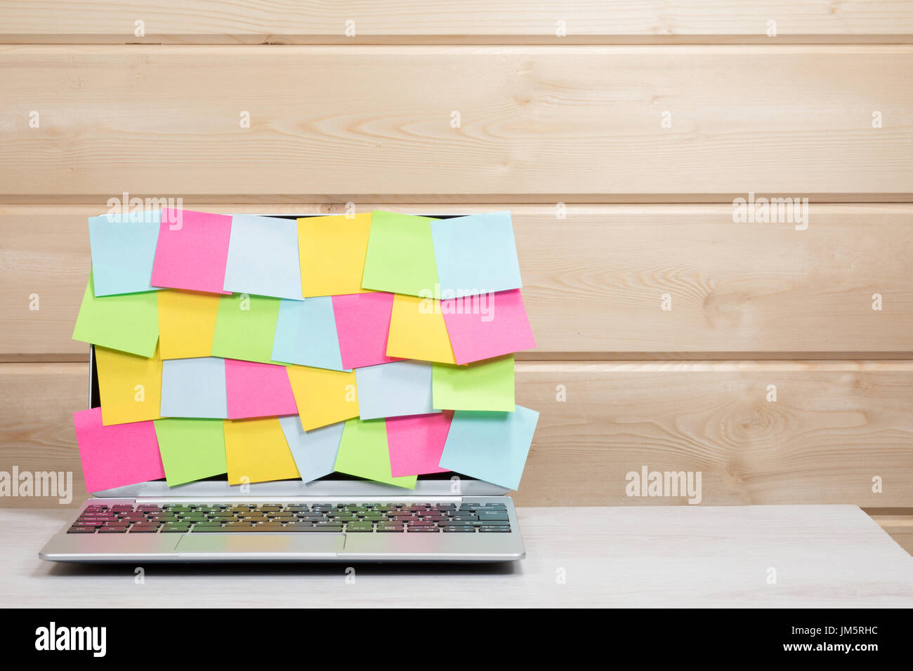 Laptop screen covered in blank multicolored sticky notes against a ...